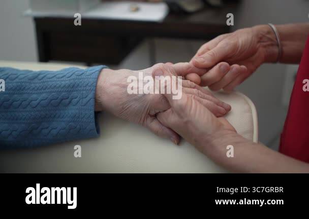 A caregiver gently holds the hand of an elderly woman, fostering ...