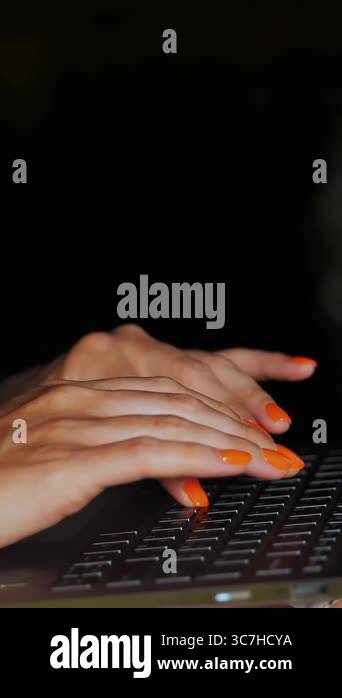 Close-up, female hands with bright red nails, are typing on a laptop ...