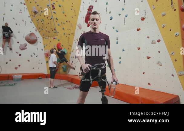 Medium portrait of young athletic man with prosthetic leg looking at camera standing at modern ...
