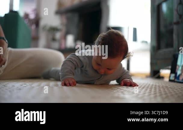 Baby lying on mat indoors, feeling surface with hands and face, sensory ...