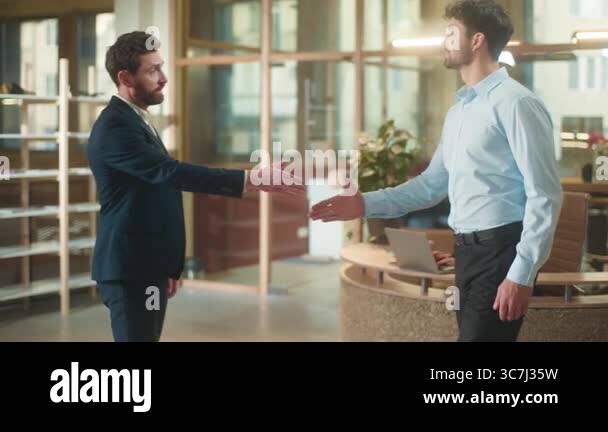 Two Caucasian men meeting in office handshaking business partners guys greeting hello gesture ...