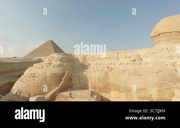 Majestic sphinx guarding pyramid of khafre, standing tall against clear blue sky in historic ...
