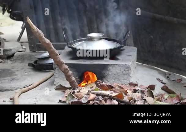 Curry cooking on a traditional clay stove fueled by dry leaves and cow ...
