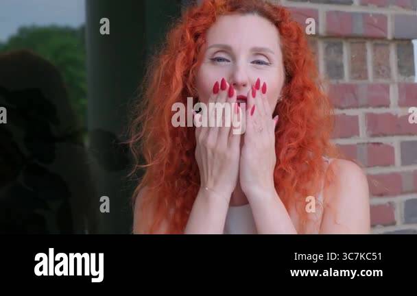 A lively redheaded woman joyfully blowing affectionate kisses ...