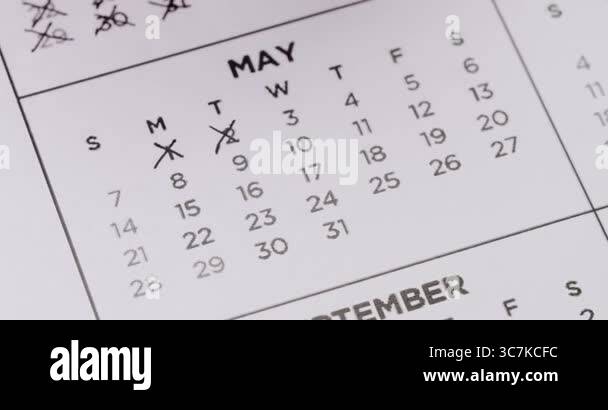 Person crossing off days of month of May on a calendar with a black pen ...