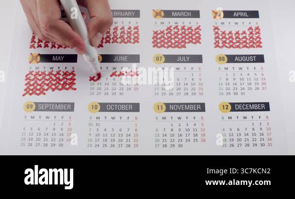 Close-up of a hand marking dates off a calendar with a red pen. Concept ...