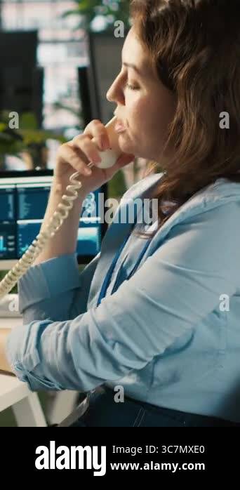 Vertical video Worker in office using landline phone to talk with ...