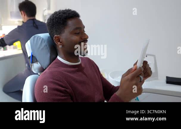 Young man checks his smile after a dental procedure, using both a ...