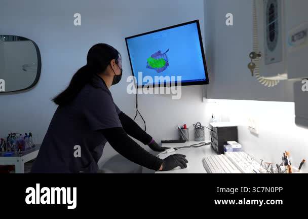 Dentist wearing face mask and shield analyzing a 3d x ray scan of teeth ...