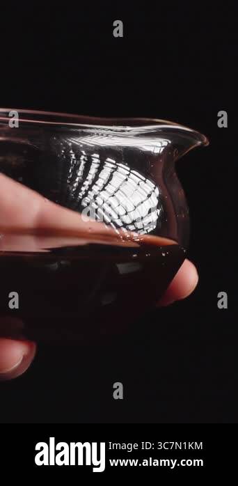 A hand firmly holding a glass jug that is filled to the brim with a ...