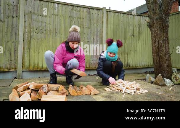 Mother and daughter sorting firewood, arranging logs and kindling for ...
