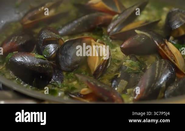 Steamed mussels with herbs and sauce on a hot pan while cooking Italian ...