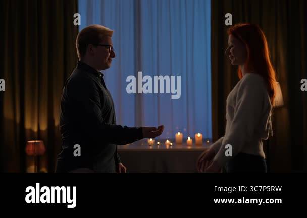 A couple enjoys a romantic evening with warm candlelight, creating a ...