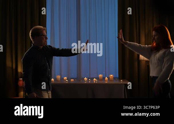A cute young couple dancing merrily in a dark room with candles lit ...