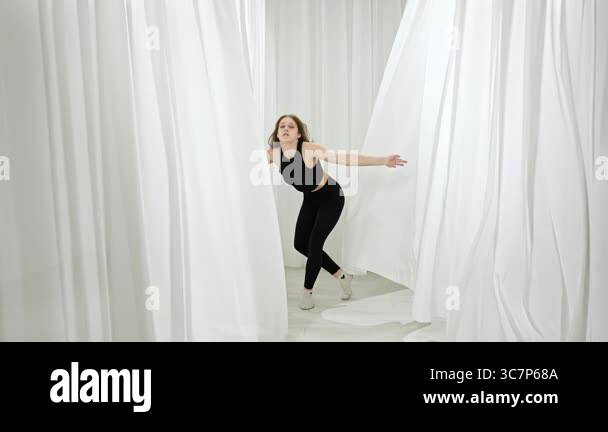 A dancer in black attire gracefully moves through a space with flowing ...