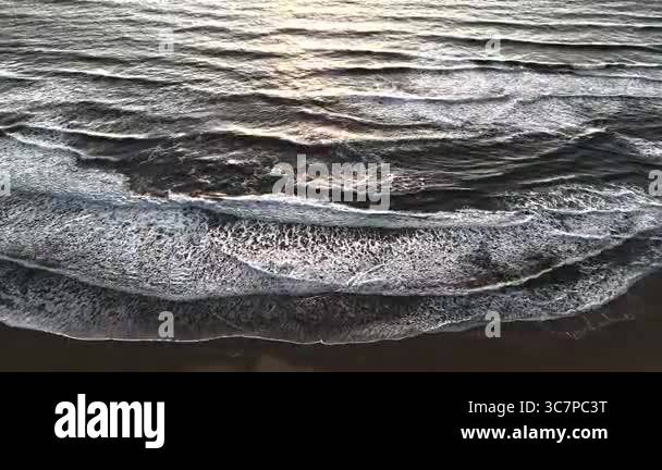 Aerial view of textured ocean waves breaking in layers on a dark wet ...