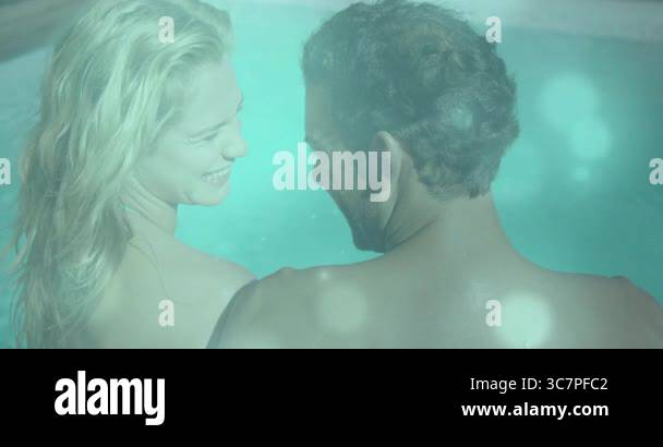 In swimming pool, couple relaxing and embracing, sharing joyful ...
