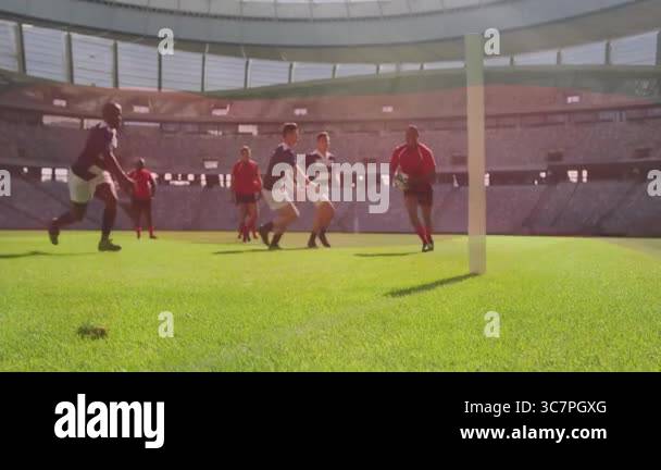 Diving to catch ball, rugby player in red uniform on stadium field ...
