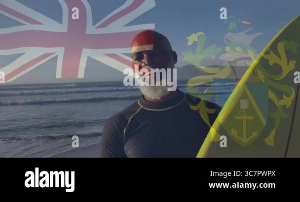 Holding surfboard with Union Jack, smiling man standing on beach with ...