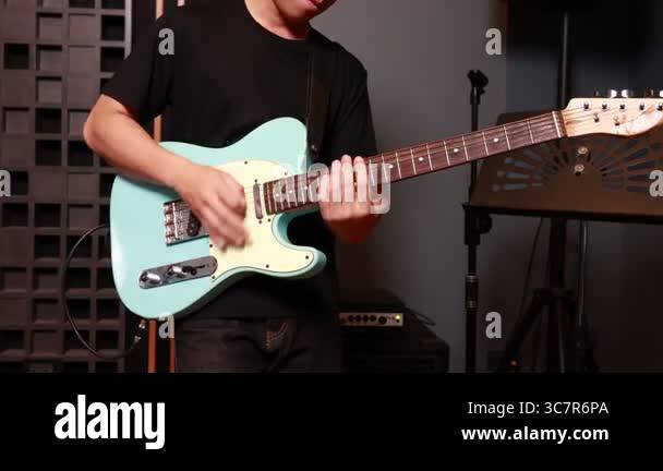 Asian male musician performing solo with light blue electric guitar in ...