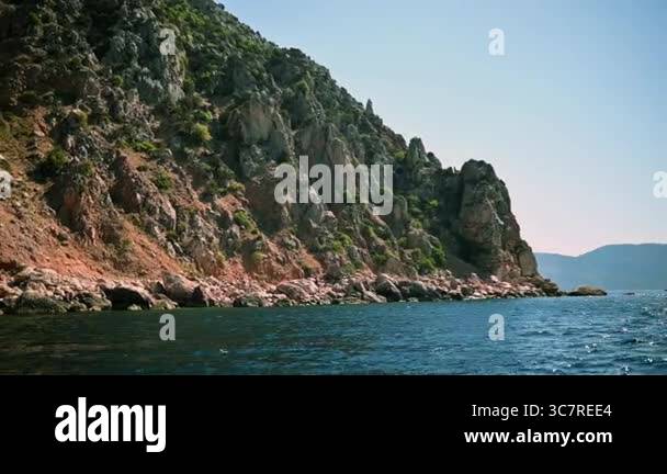 Majestic rocky cliff towering over deep blue sea. Sunlight illuminates ...