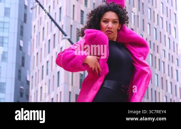 Graceful dancer with curly hair wearing a pink coat, expressing ...