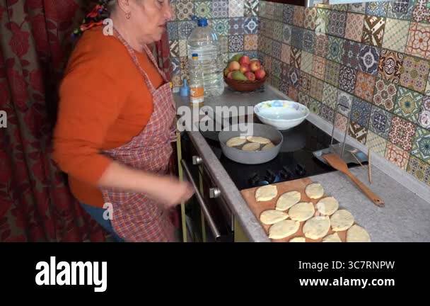 Grandma is frying pies in boiling oil on frying pan. Pie fried, food ...