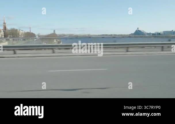 Riga, Latvia - April 5, 2025 - Driving over a city bridge with view of ...