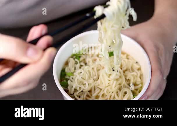 Close up of a female eating simple ramen noodles with chopsticks ...