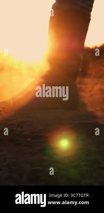 Farmer in boots walks across the field. close-up. legs in farming boots ...