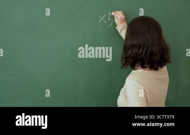 A teenage girl solves a math problem on the board during a math lesson ...
