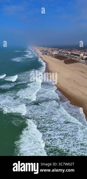 Aerial drone shot captures a vast sandy beach with ocean waves and a ...