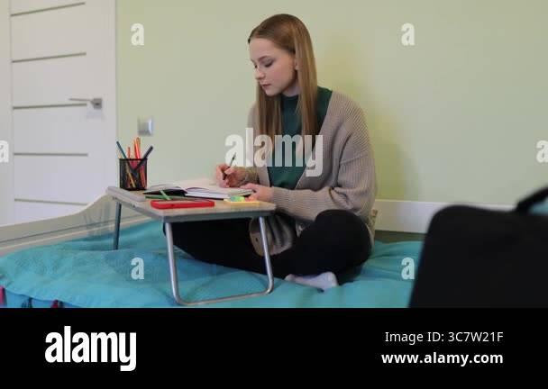 A young student is focused on her studies while seated comfortably on ...