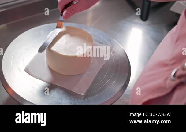 Female professional hands levels cream on baked sponge cake using ...