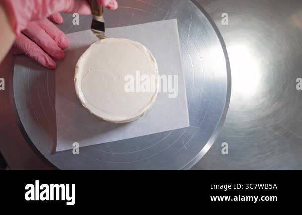 Female professional hands levels cream on baked sponge cake using ...