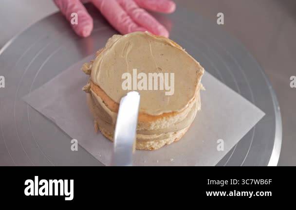 Female professional hands levels cream on baked sponge cake using ...