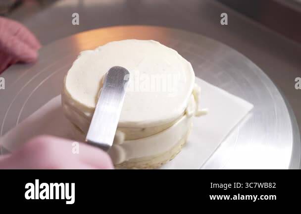 Pastry chef leveling cake sides with cream. Confectioner working with ...