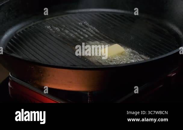 a piece of butter is melted in a frying pan, close up, slow motion ...