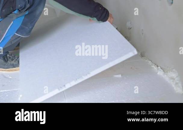 Construction worker placing and cutting styrofoam insulation panels ...