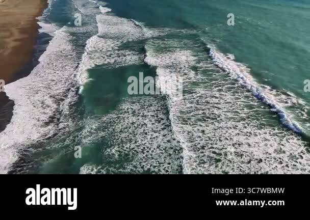 Turquoise ocean waves rolling rhythmically and crashing onto sandy ...