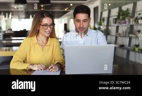 Focused busy young managers working at laptop together, watching ...