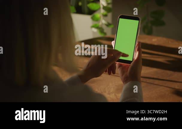 Close-up of woman using smartphone with green screen, performing single ...