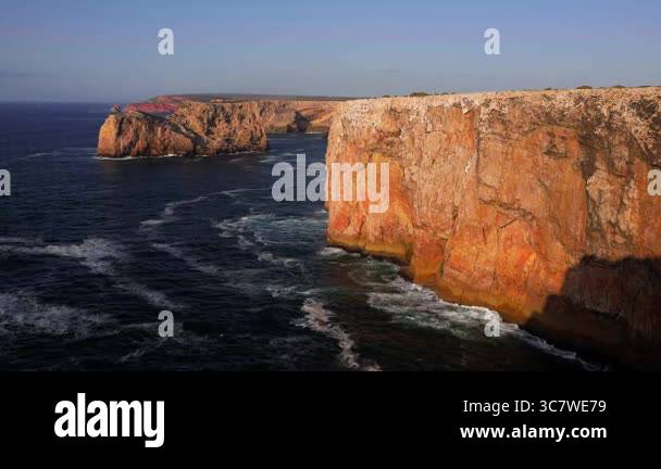 Dramatic orange limestone cliffs tower over the Atlantic Ocean along ...