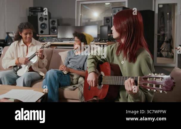 Caucasian red-haired teenage guitarist rehearsing song with African ...