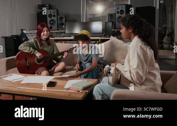 Three positive teenagers discussing new song pointing at sheet music ...