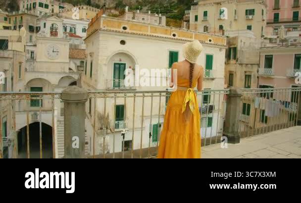 Woman overlooking old town buildings and central clock tower in Atrani ...