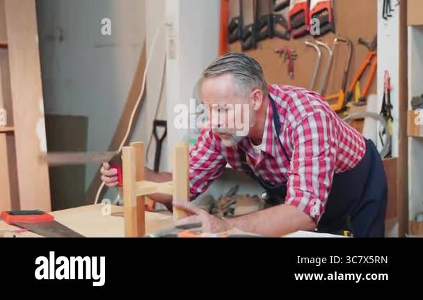 Senior carpenter uses a ruler and set square to measure and assemble a ...