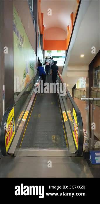 A mall escalator in motion with several men and women inside. The ...