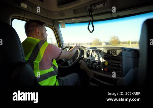 Professional Semi Truck Driver wearing a safety vest is riding a truck ...