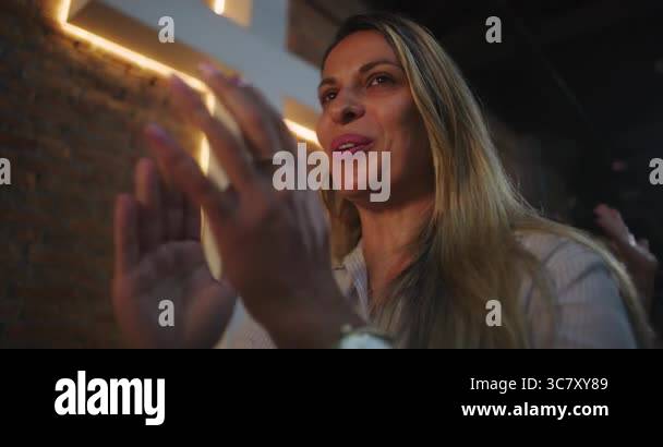 Woman smiling with hands clasped in applause, glowing cross on brick ...